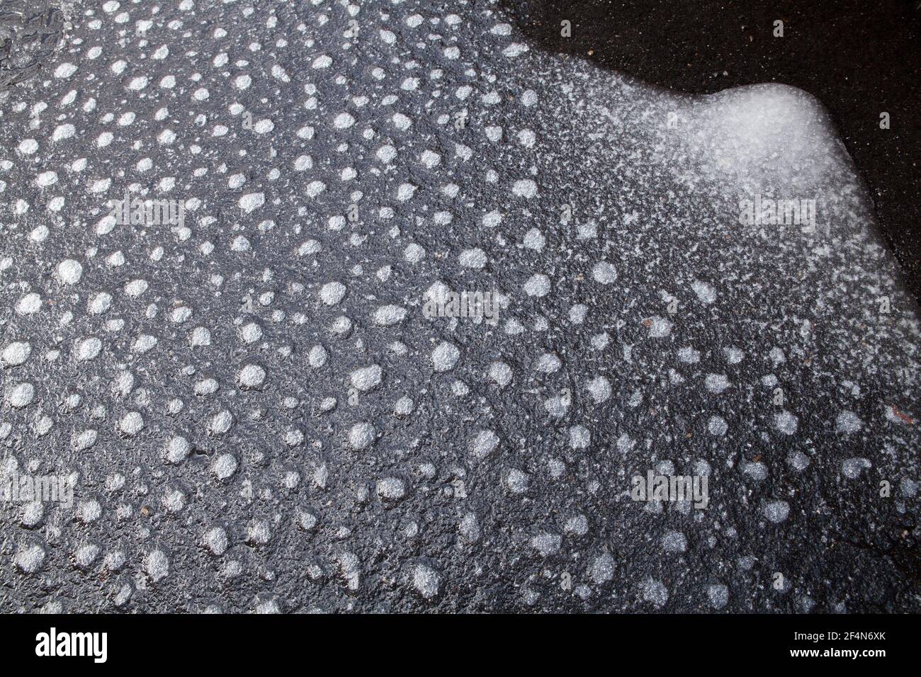 Strange dots on a sheet of ice on asphalt Stock Photo - Alamy