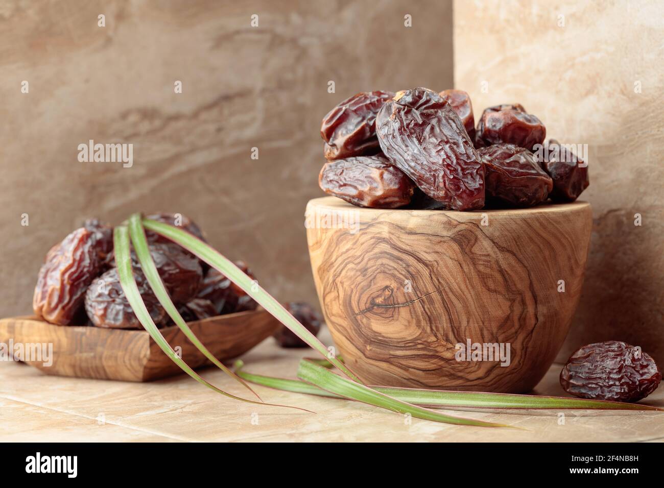 Fresh dates fruit in a wooden dish on a beige ceramic table Stock Photo ...