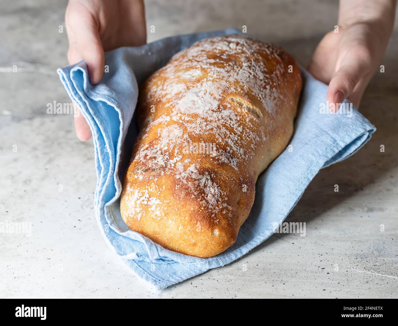 Female baker holds home made artisan organic bread fresh from the oven ...
