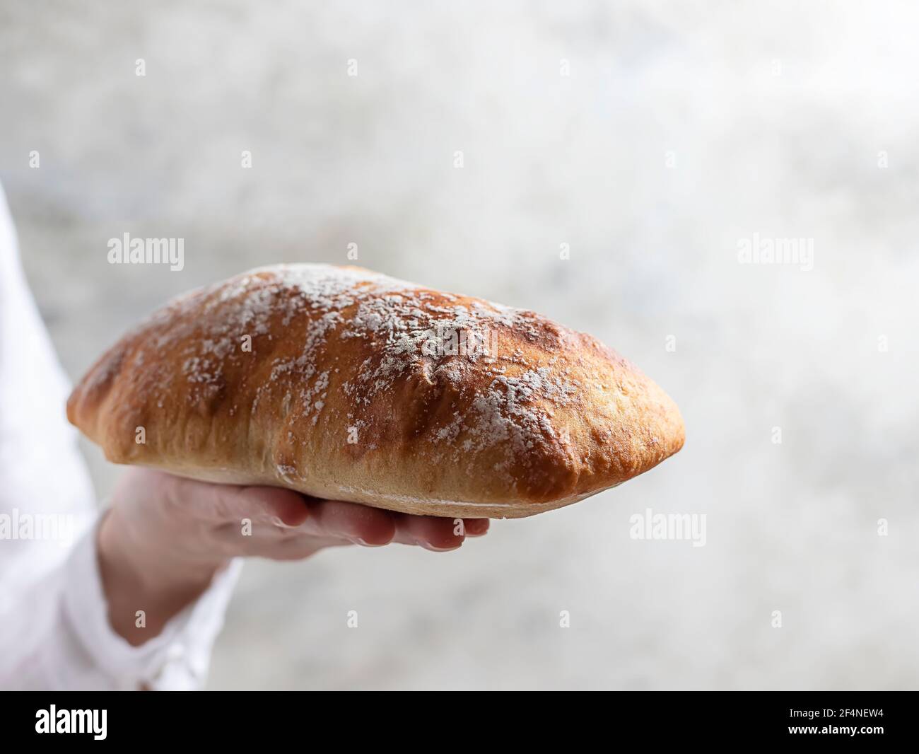 Female baker holds home made artisan organic bread fresh from the oven ...
