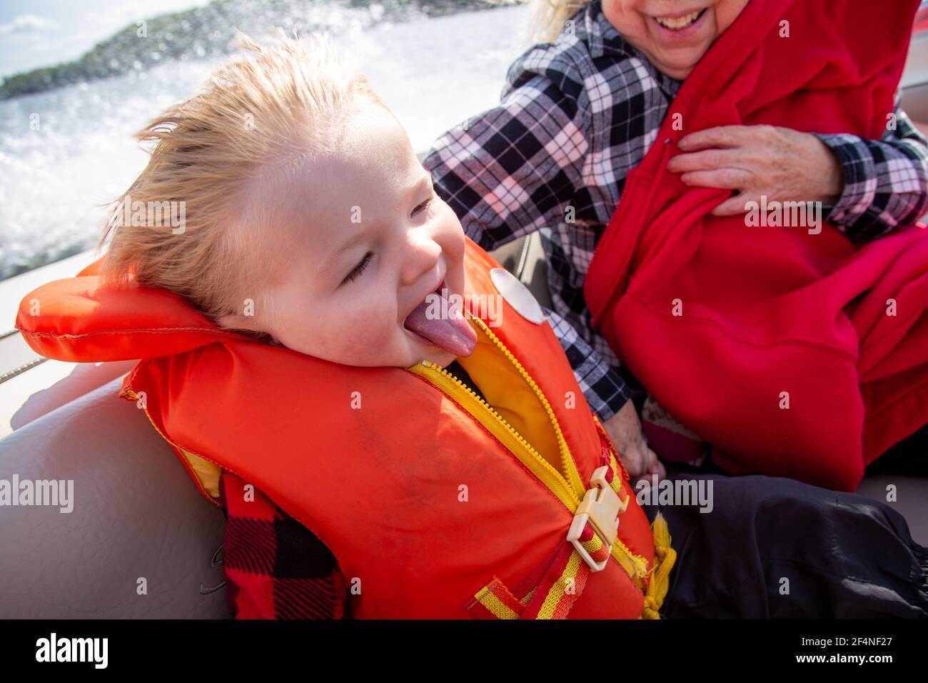 Happy baby wearing a life jacket, enjoying a motor boat ride at the ...