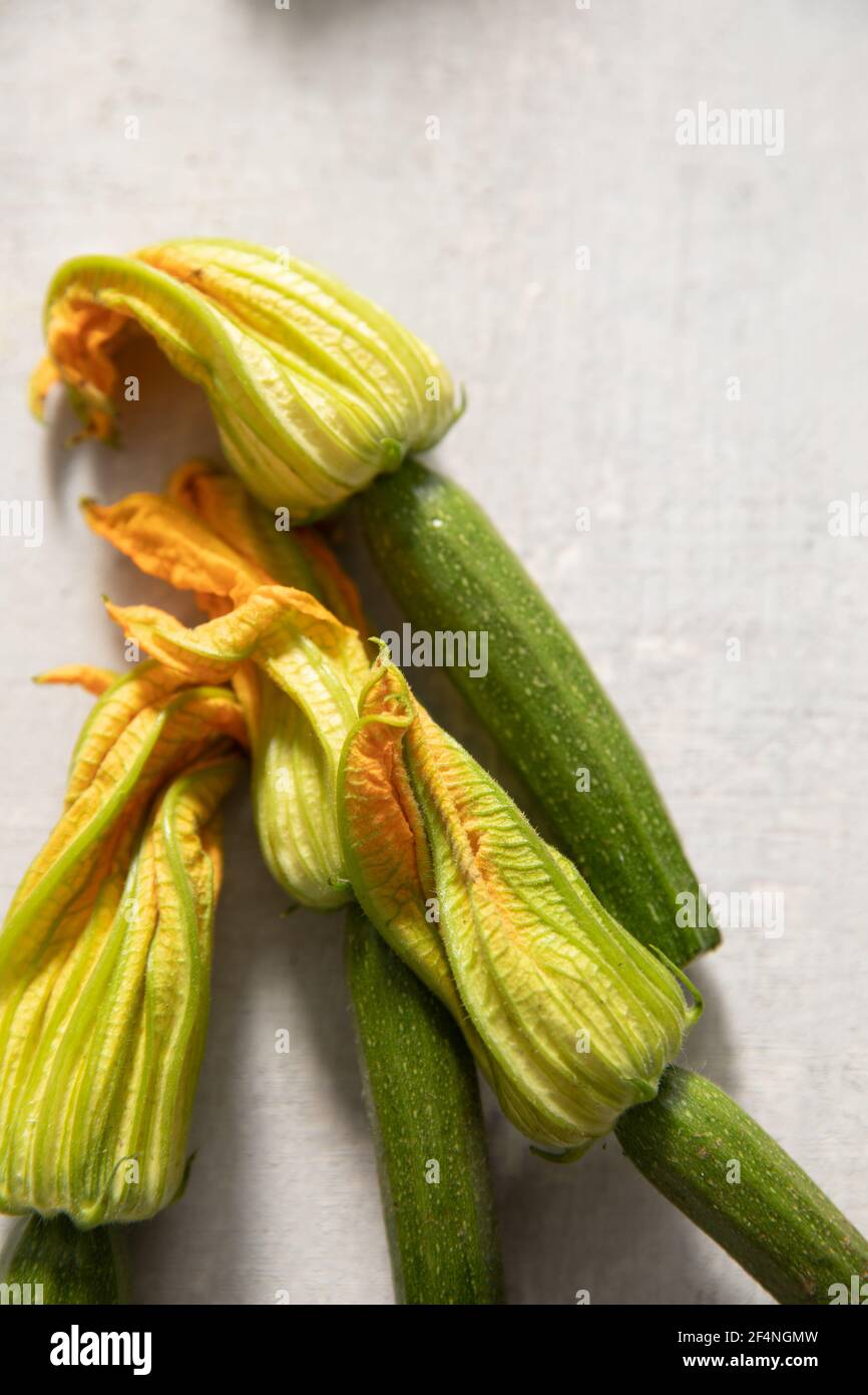 Top view of fresh courgettes or zucchini with flowers on a white ...
