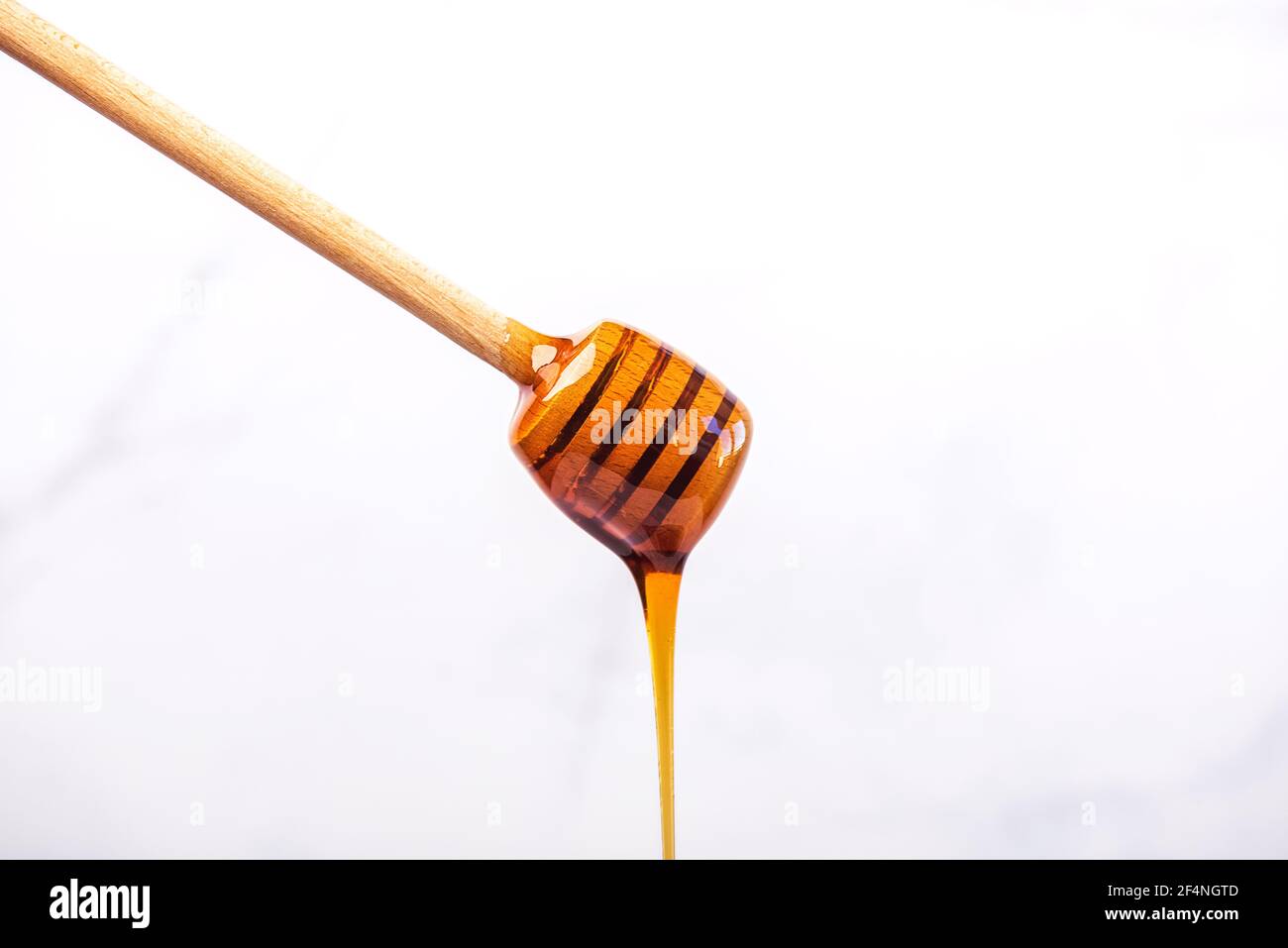 Honey dripping from a wooden spoon for honey on a white background ...