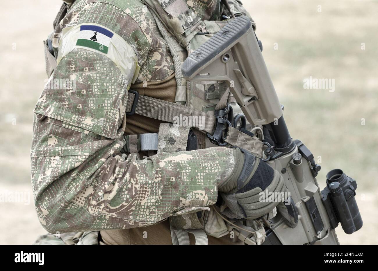 Soldier with assault rifle and flag of Lesotho on military uniform ...