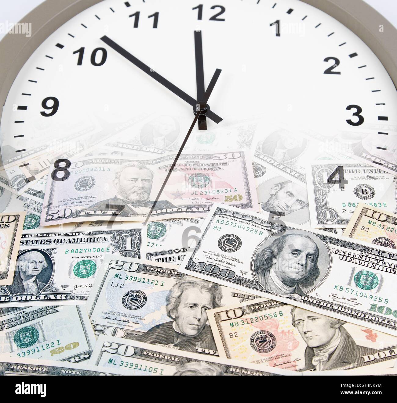 Clock on assorted American banknotes. Time is money idea Stock Photo ...
