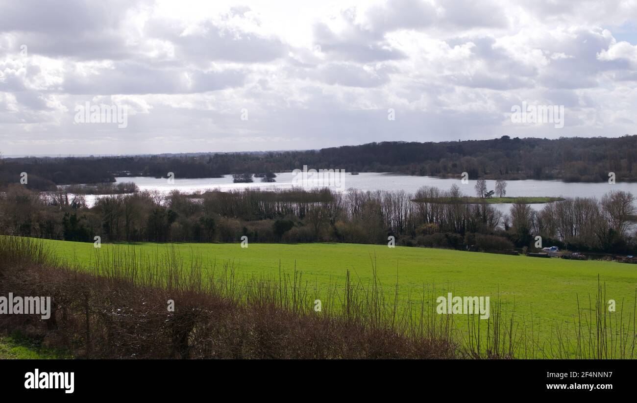 View over English countryside in spring showing lake grass and sky ...