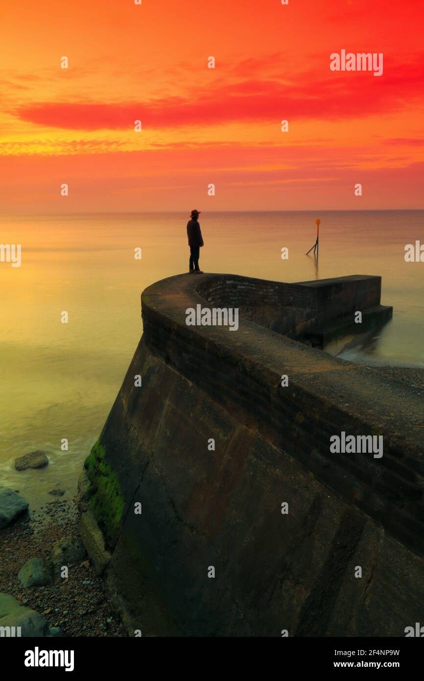 Silhouette of a man standing on jetty at sunrise. Book cover concept ...