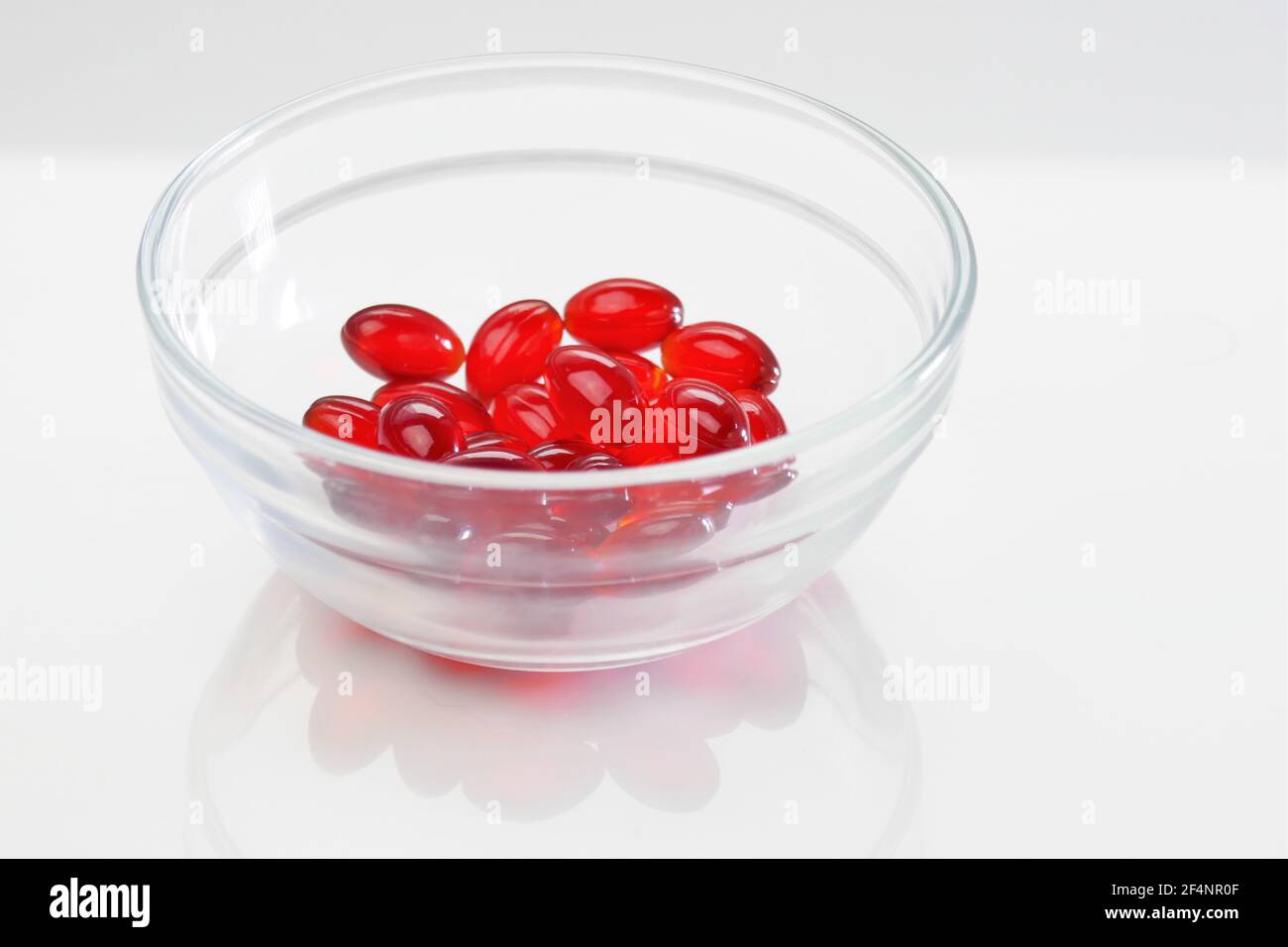 Krill oil capsules. Red gelatin capsules with krill oil in a glass ...