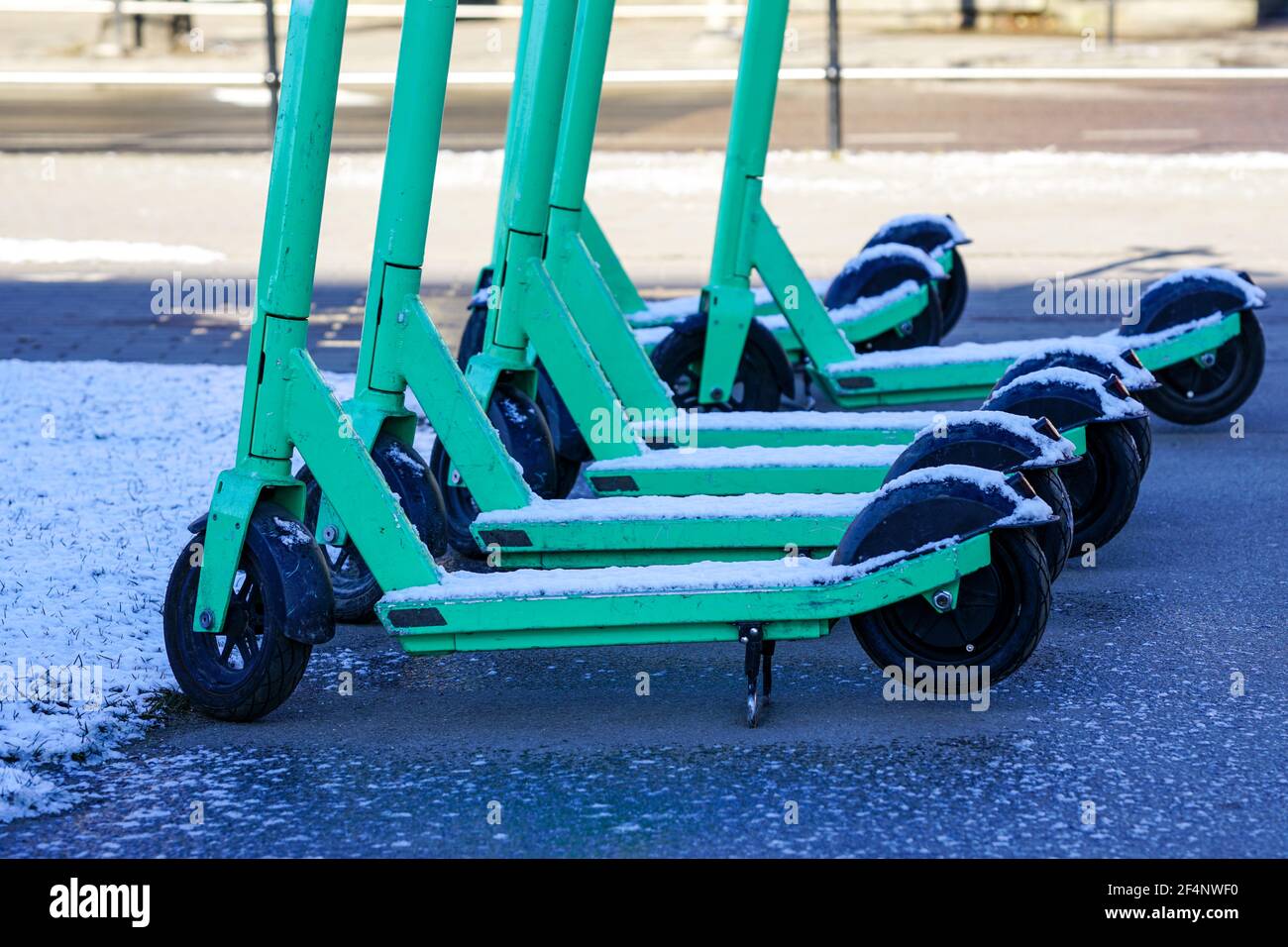 snow covered rental electric scooters on a city street in winter Stock ...