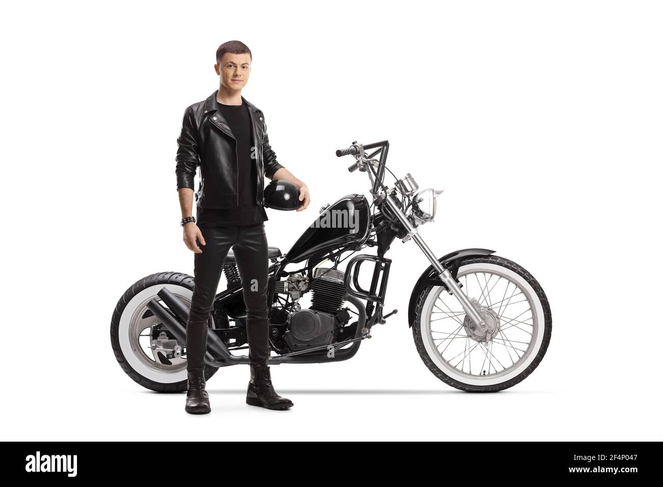 Full length portrait of a guy holding helmet and posing with a chopper ...