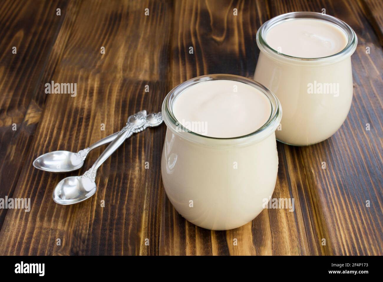Homemade ryazhenka in the glass jars on the brown wooden background ...