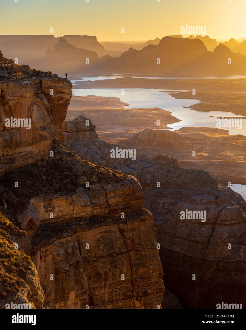 Vertical shot of a person standing on a rock and observing the ...