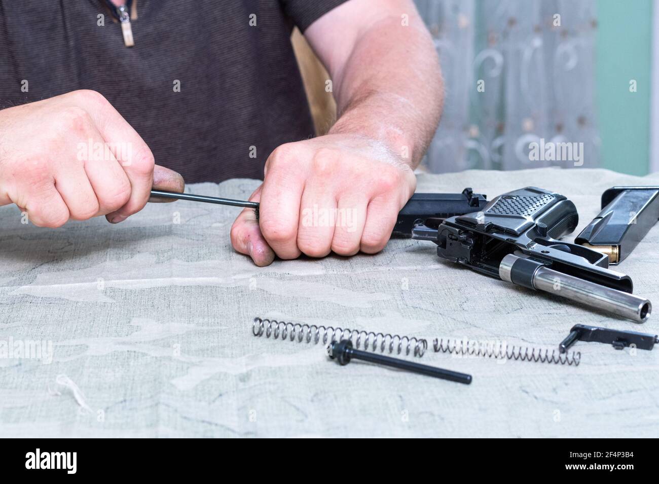 The man is cleaning the receiver. The barrel and barrel of a pistol ...
