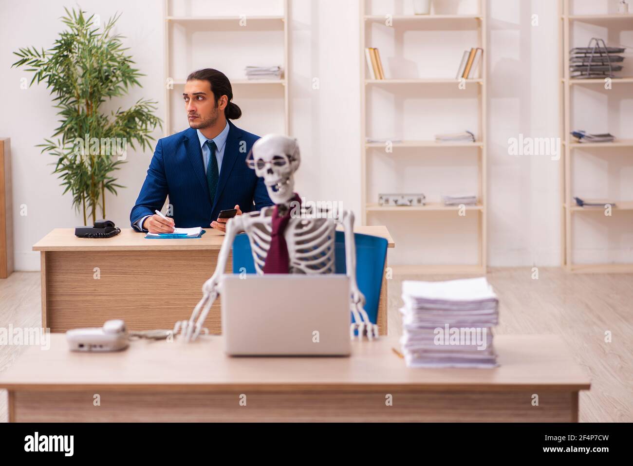 Dead employee working in the office in funny concept Stock Photo - Alamy