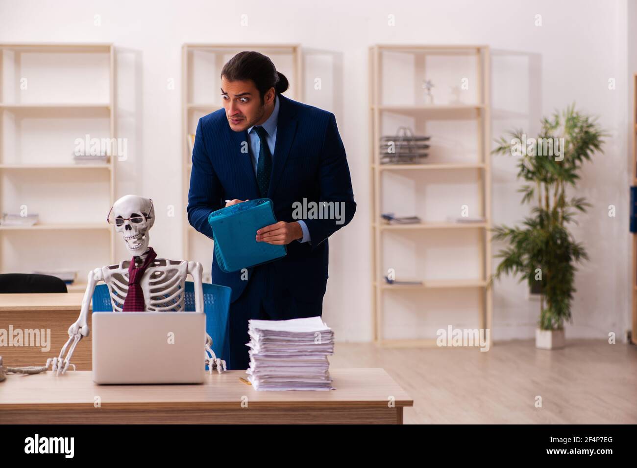 Dead employee working in the office in funny concept Stock Photo - Alamy