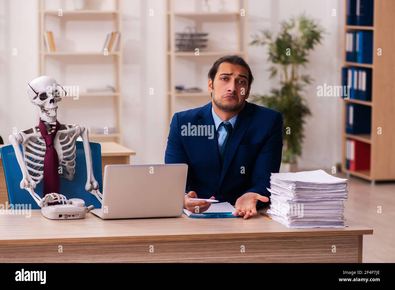 Dead employee working in the office in funny concept Stock Photo - Alamy