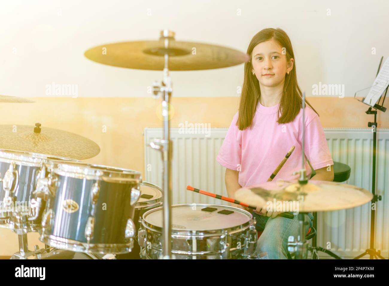 Happy girl in music therapy by playing drum kit on music room ...