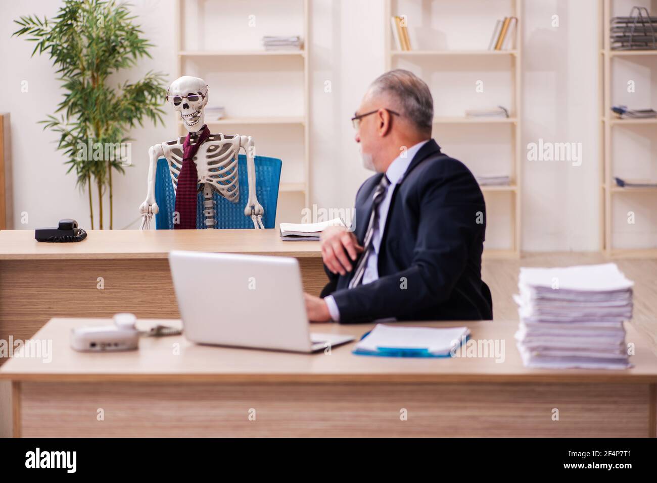 Dead employee working in the office in funny concept Stock Photo - Alamy