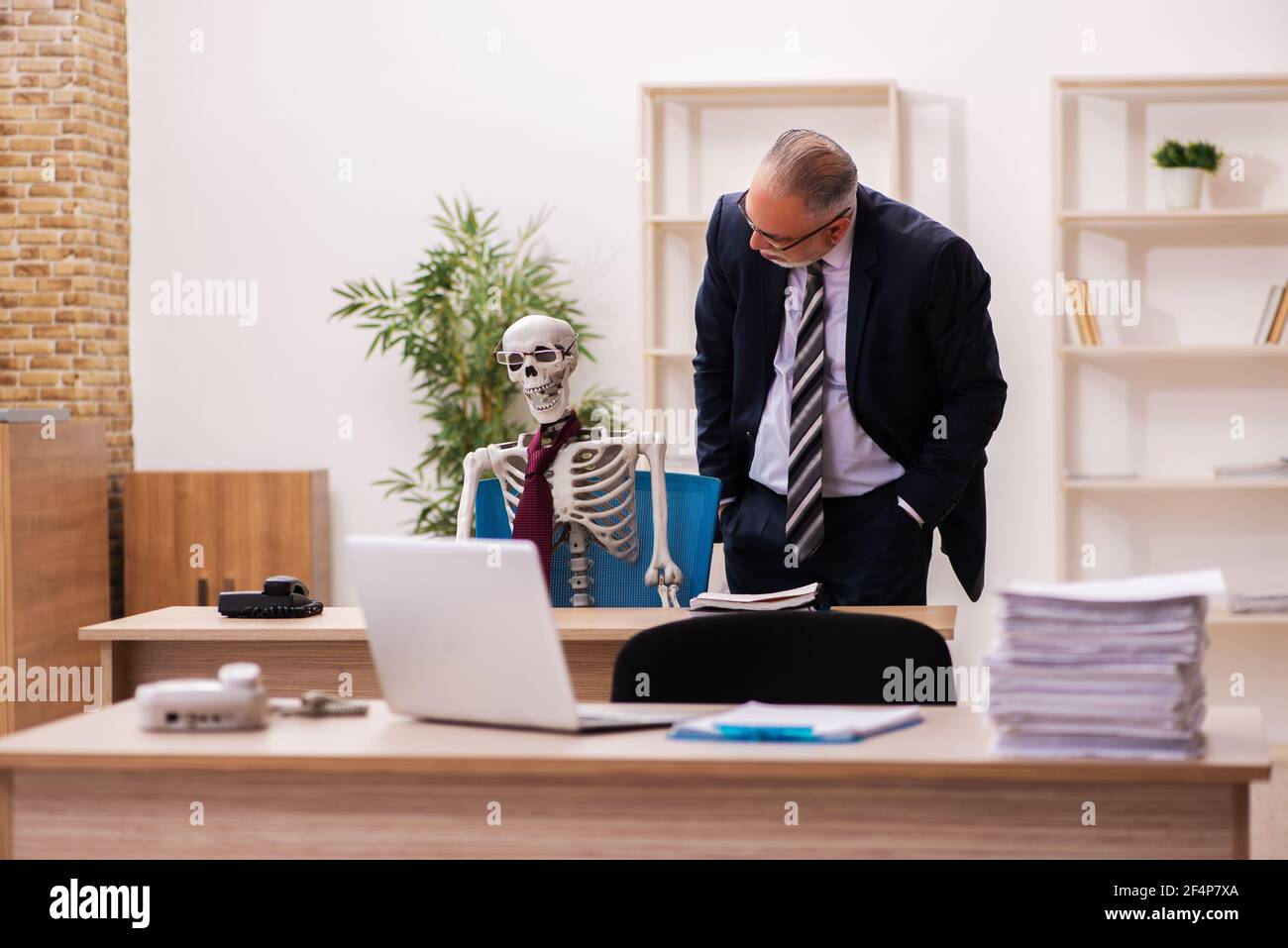 Dead employee working in the office in funny concept Stock Photo - Alamy