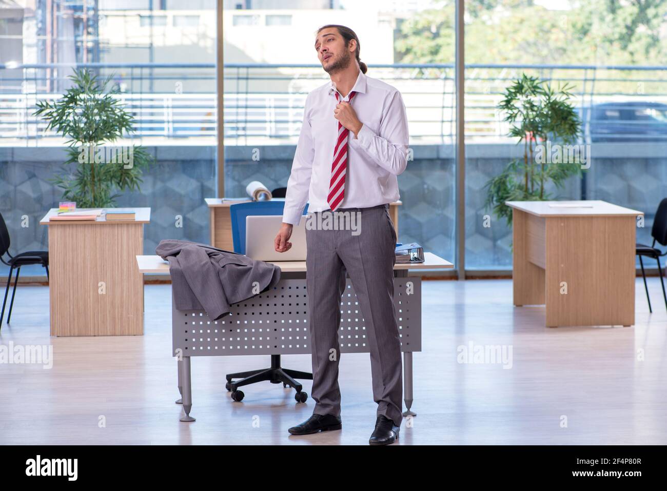 Young employee doing sport exercises at workplace Stock Photo - Alamy