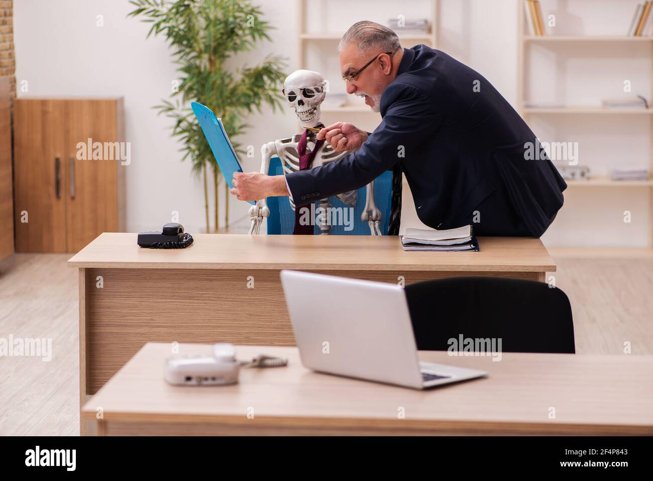 Dead employee working in the office in funny concept Stock Photo - Alamy