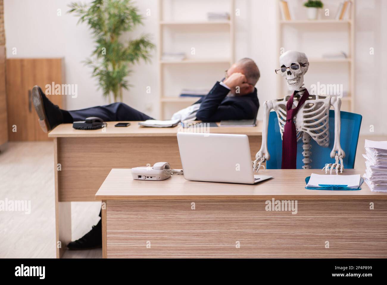 Dead employee working in the office in funny concept Stock Photo - Alamy