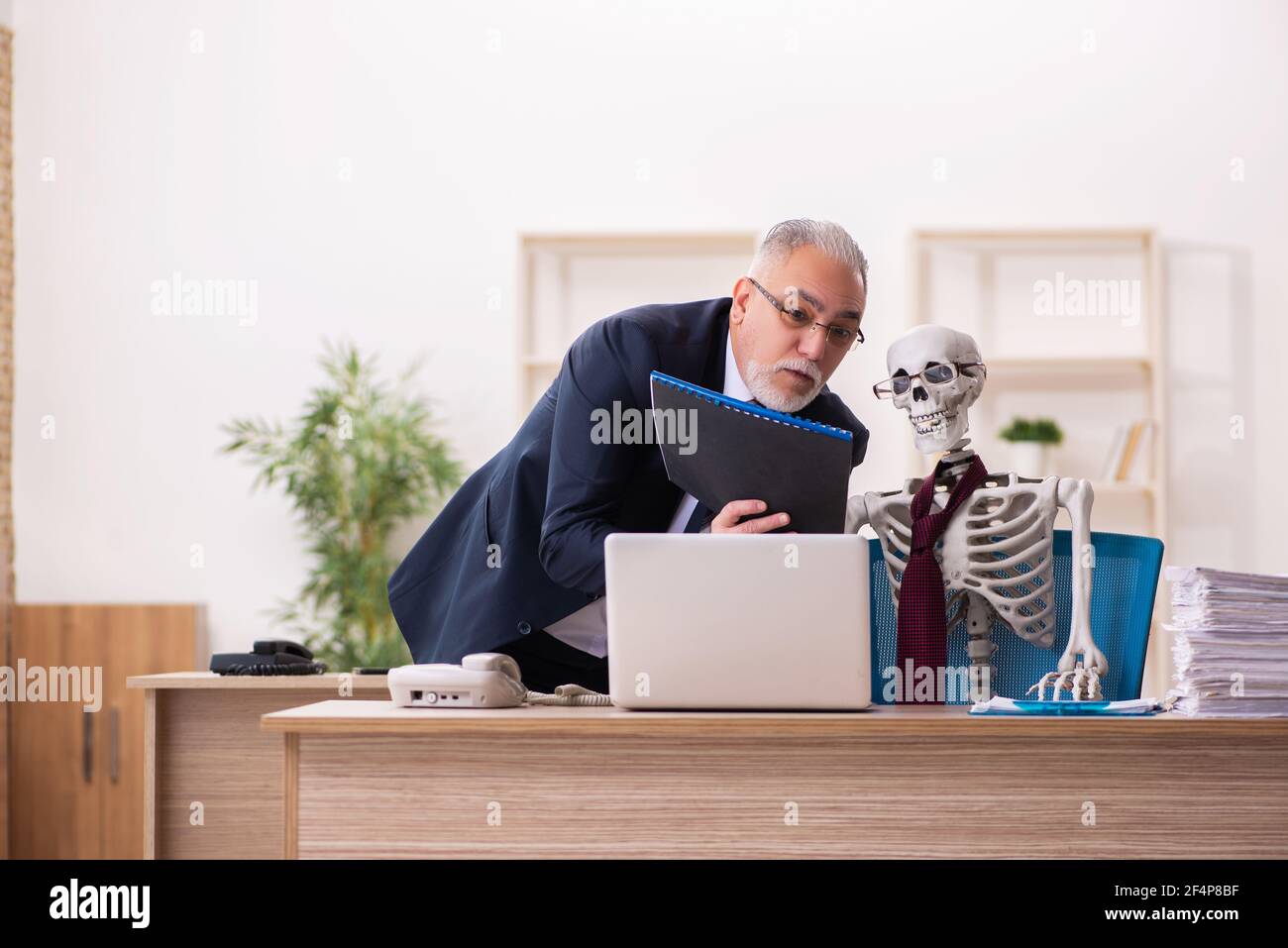 Dead employee working in the office in funny concept Stock Photo - Alamy