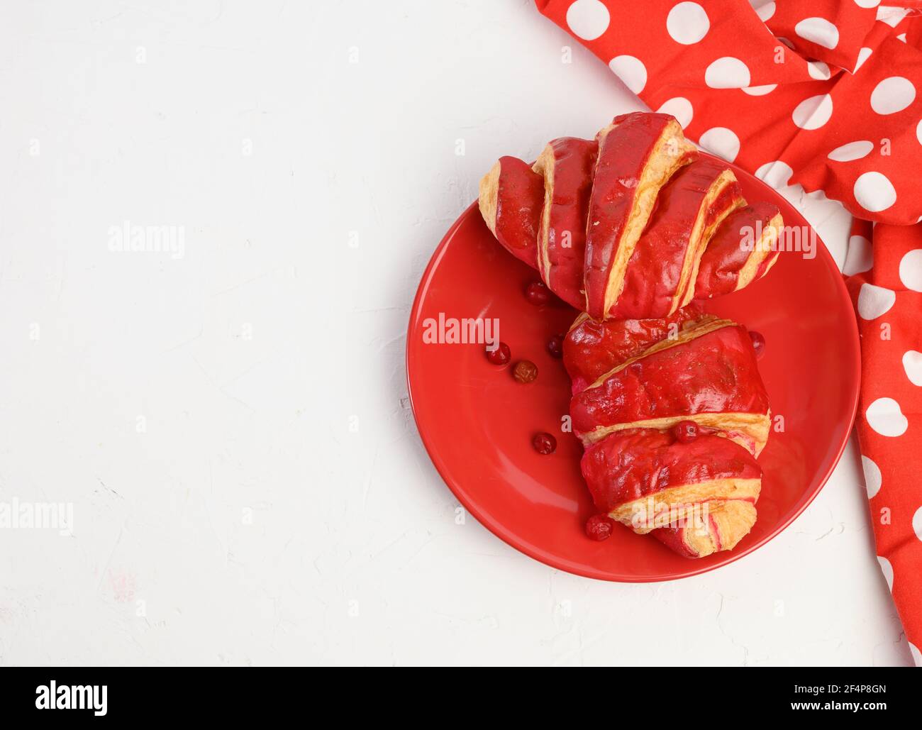 two baked croissants with cherry glaze on a red ceramic plate, white ...