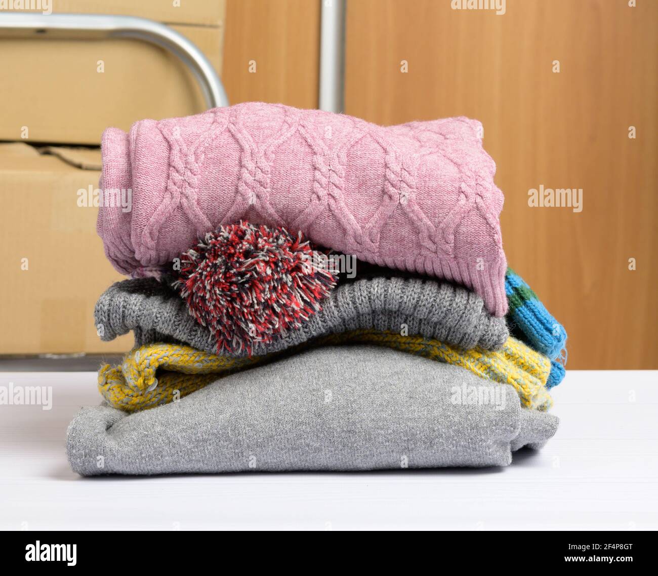 stack of clean folded clothes on white table, help and volunteering ...