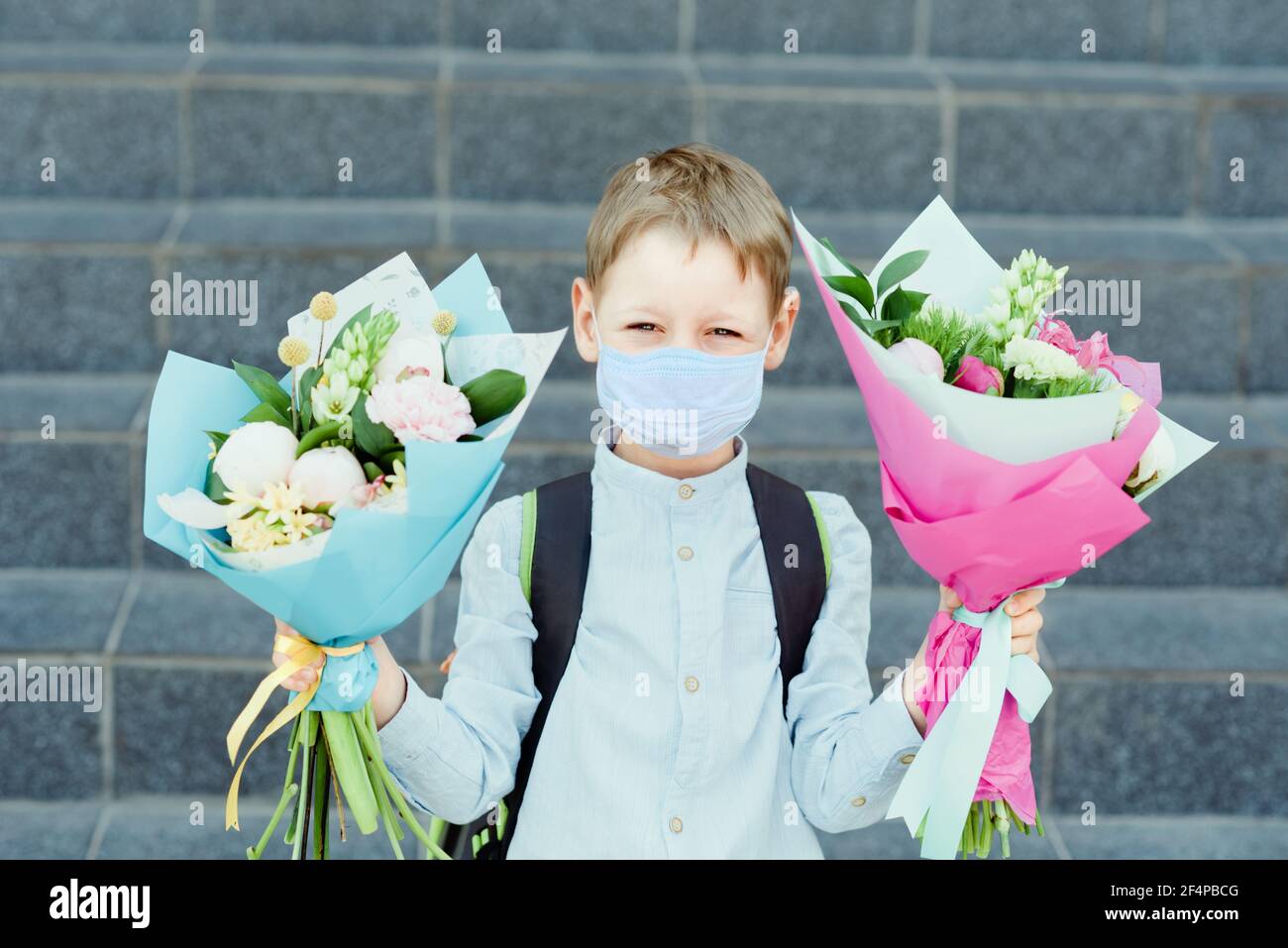 Portrait of schoolboy wearing medicine mask with bouquet in uniform on ...