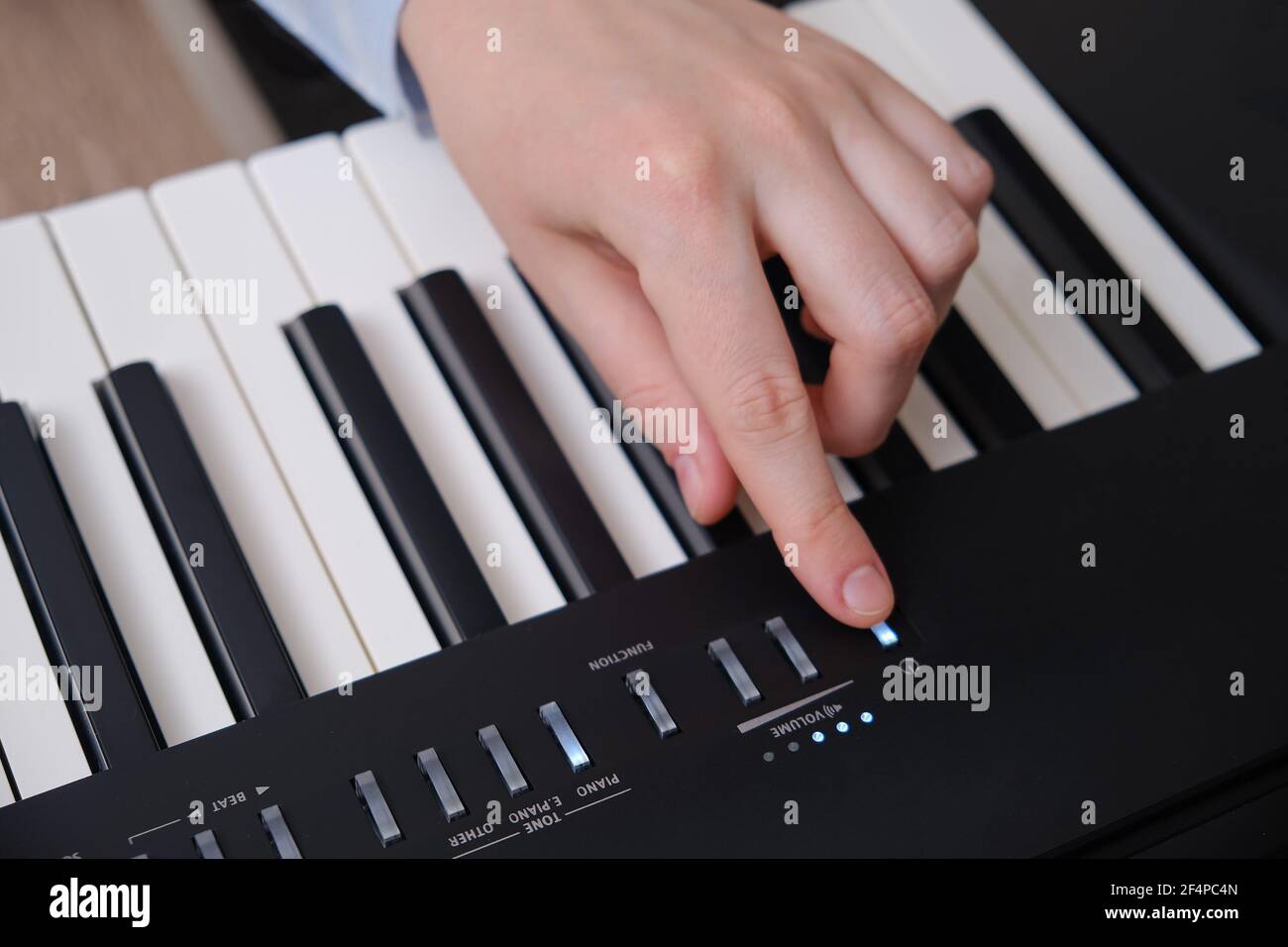 Woman turns on the electric piano, hand on the start button close-up ...