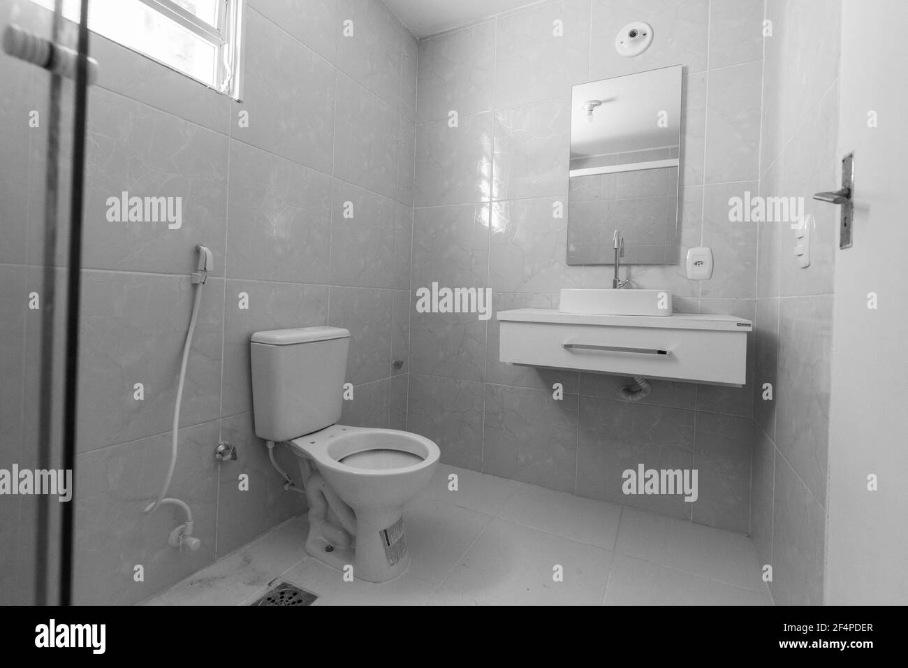 Black and white shot of an empty, well lit bathroom with a toilet ...