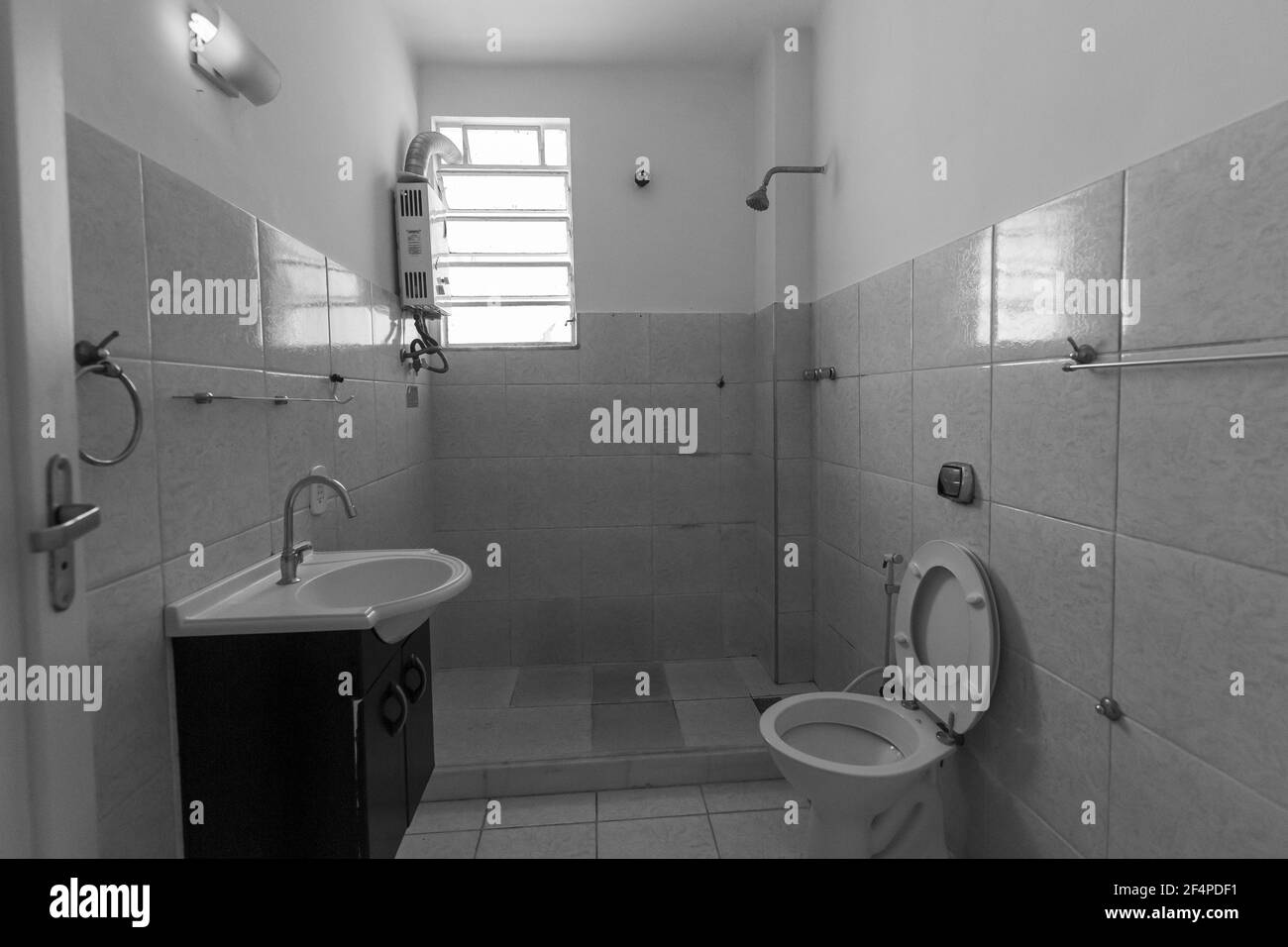 Black and white shot of an empty, well lit bathroom with a toilet ...