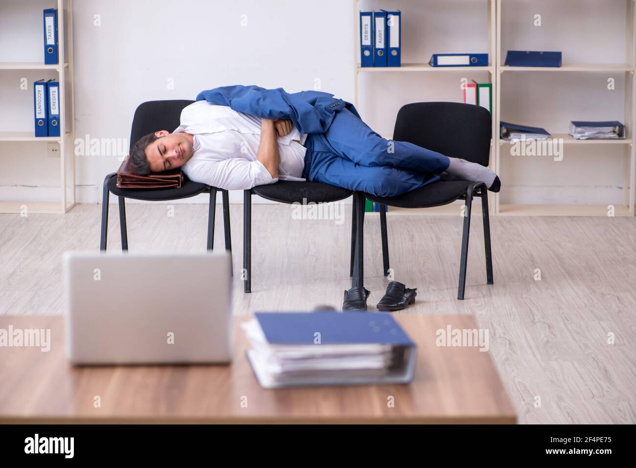 Young employee sleeping in the office on chairs Stock Photo - Alamy