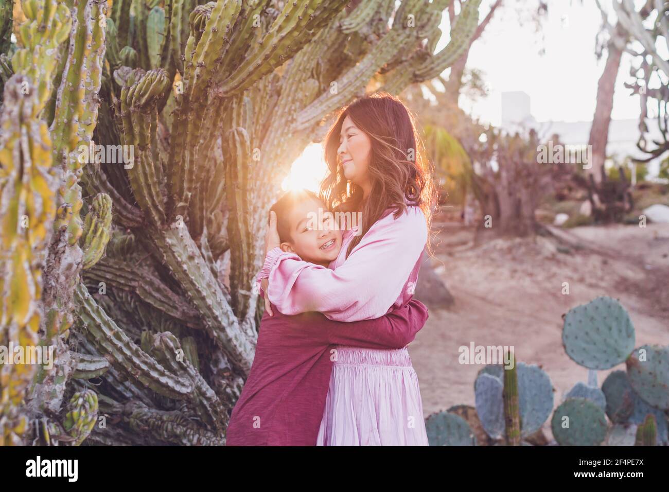 Mother hugging son in front of a big cactus with back light sun Stock ...
