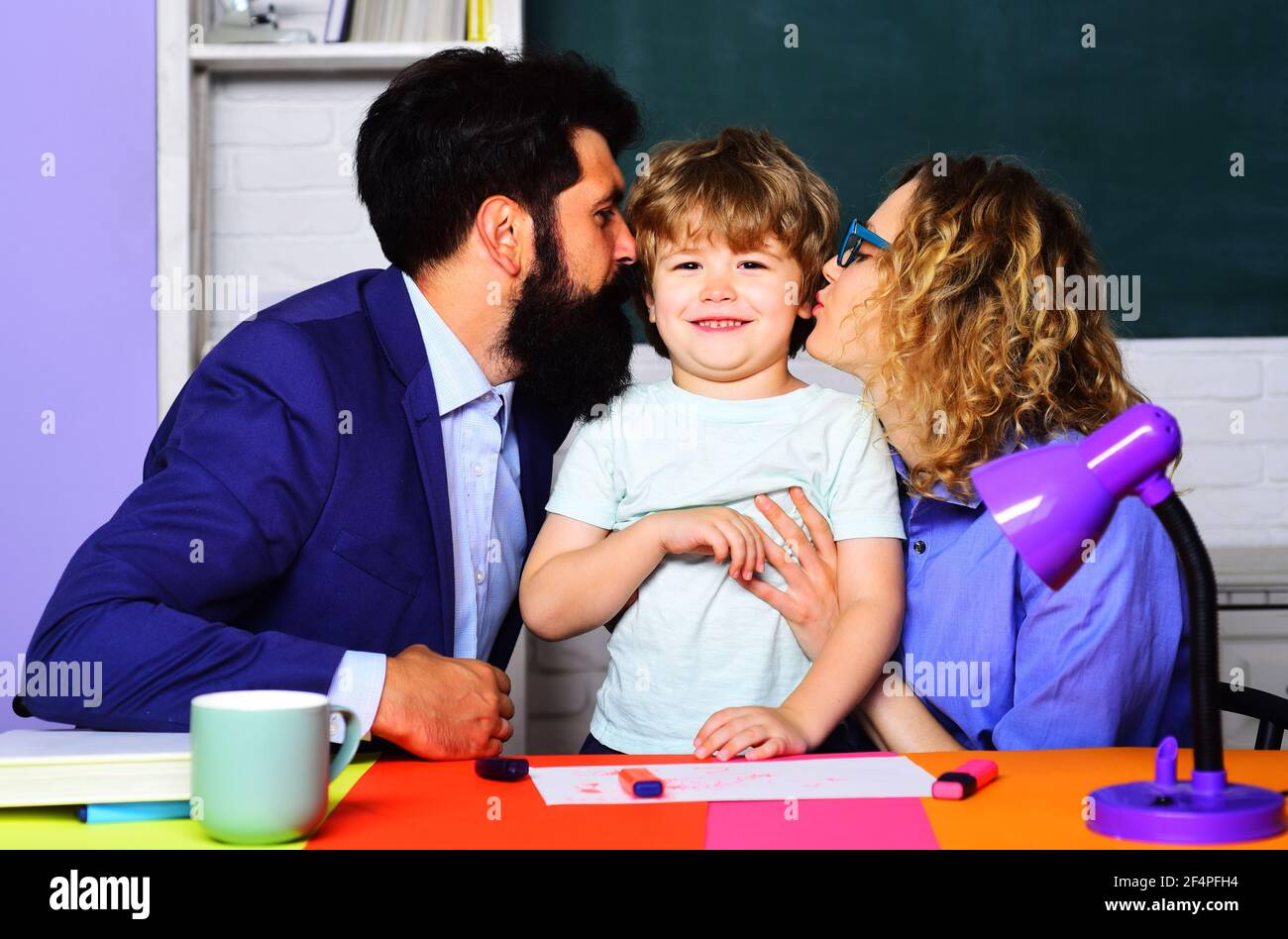 Happy parents kissing little son. Family schooling together. Children ...