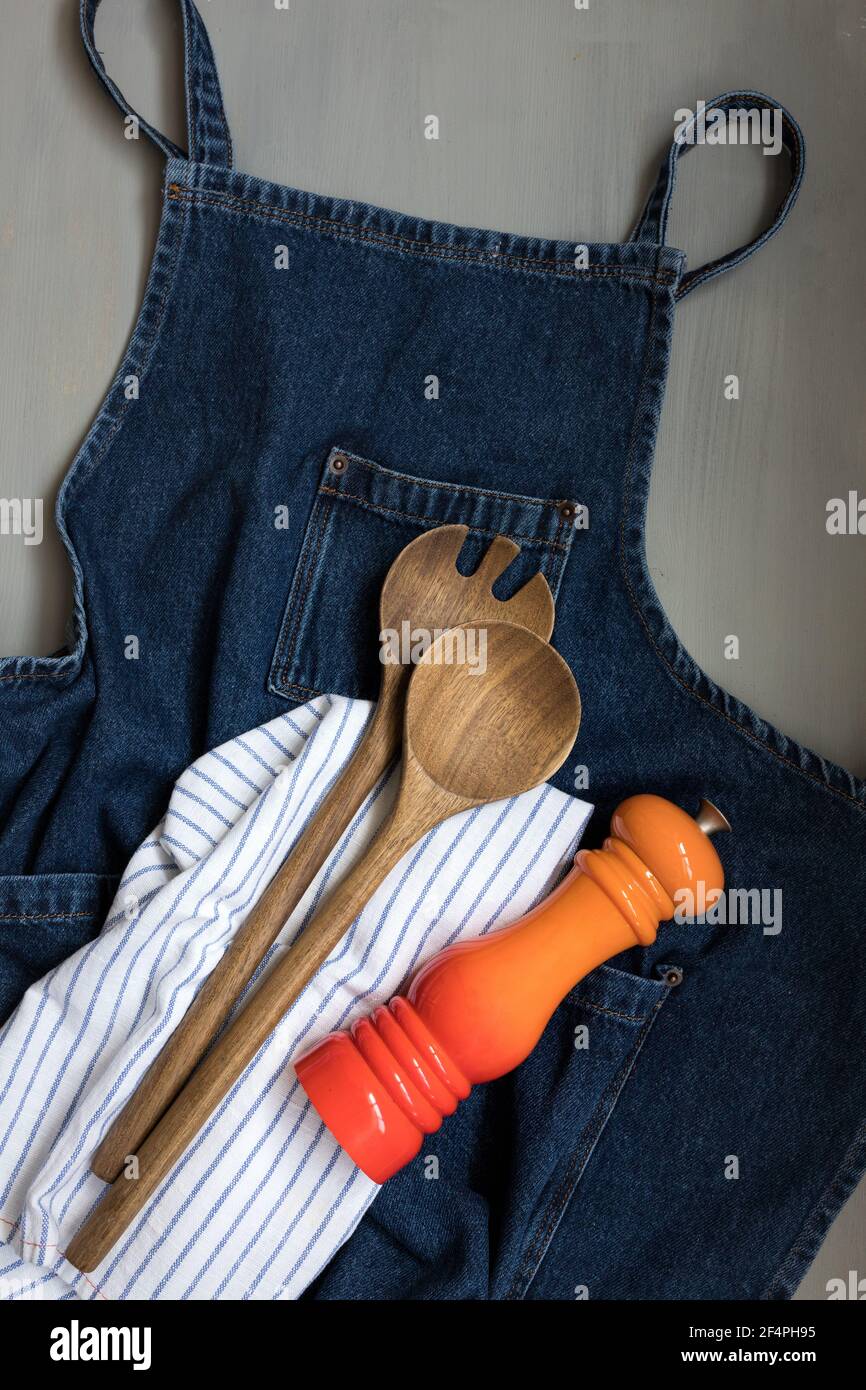 Overhead view of a denim apron with a wooden fork and spoon and an ...
