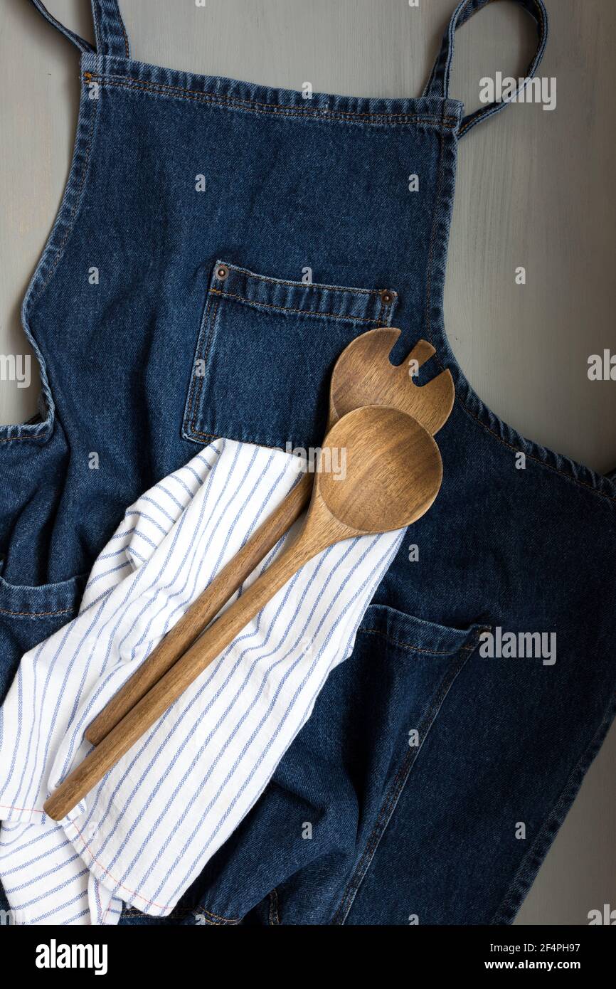 Overhead view of a denim apron with a wooden fork and spoon over a ...