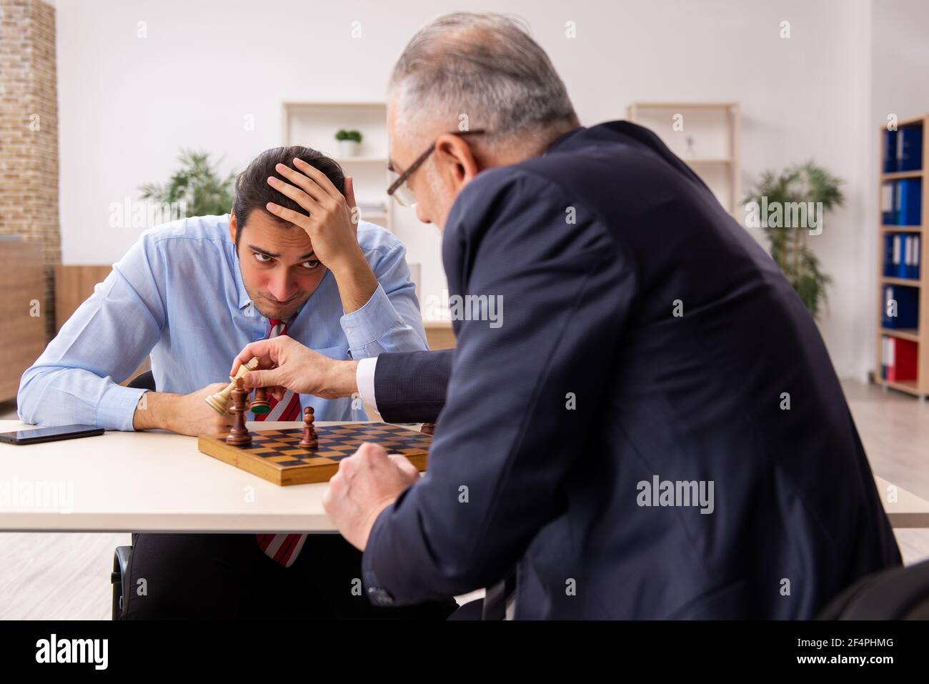 Two male employees playing chess at workplace Stock Photo - Alamy