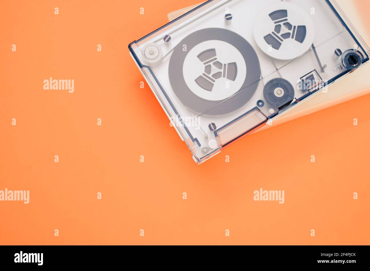 Cassette tape with a case on an orange background with space for text ...