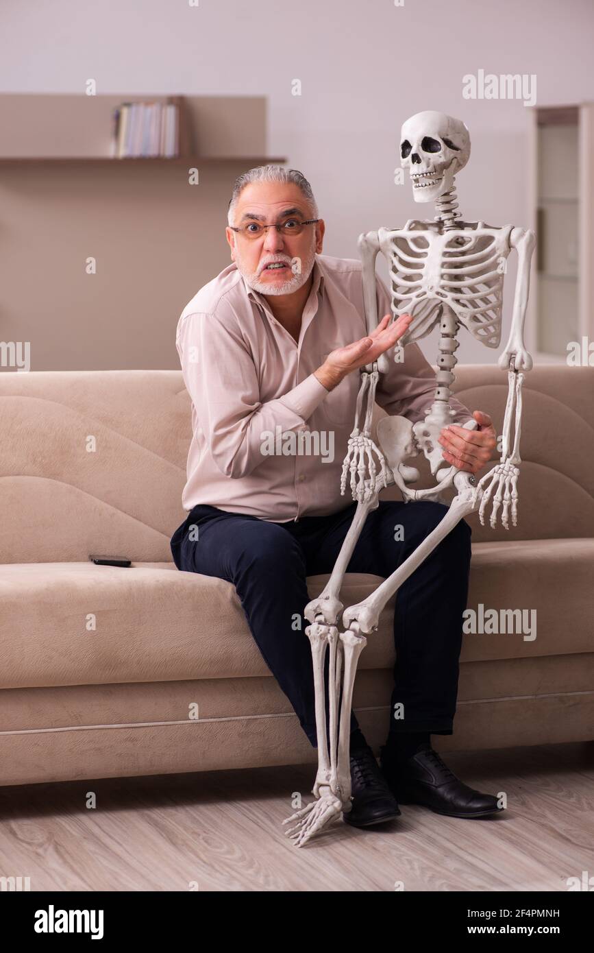 Old man sitting on the sofa with the female skeleton in undying love ...