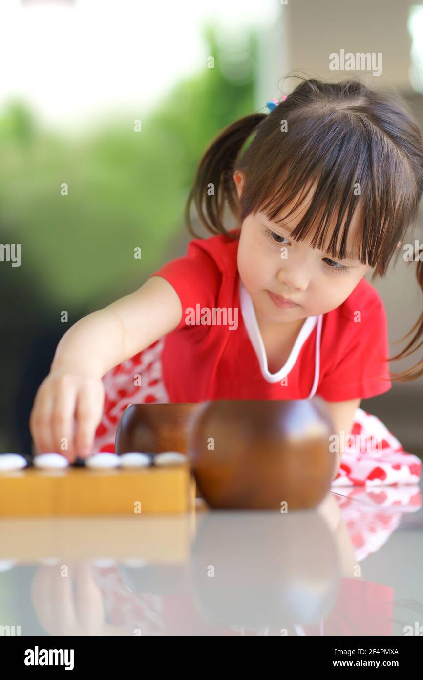 little cute asian girl in red dress playing baduk game alone outdoor ...