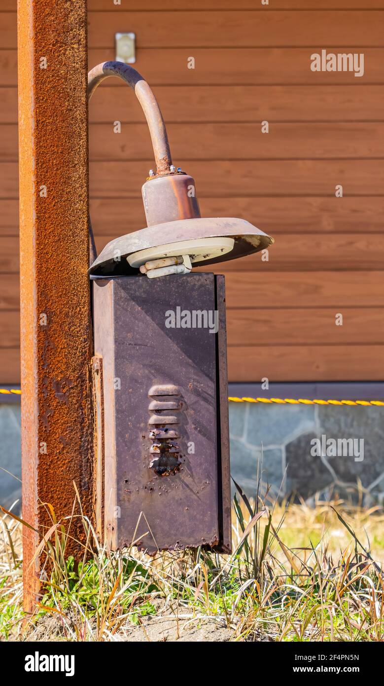 A thoroughly rusted lamppost, has lost its top and the lamp landed on a ...