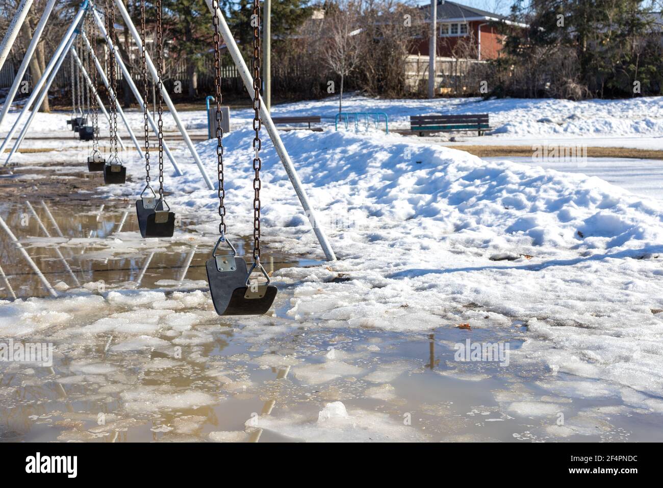 Spring in the park with swings at the playground and melting snow on ...