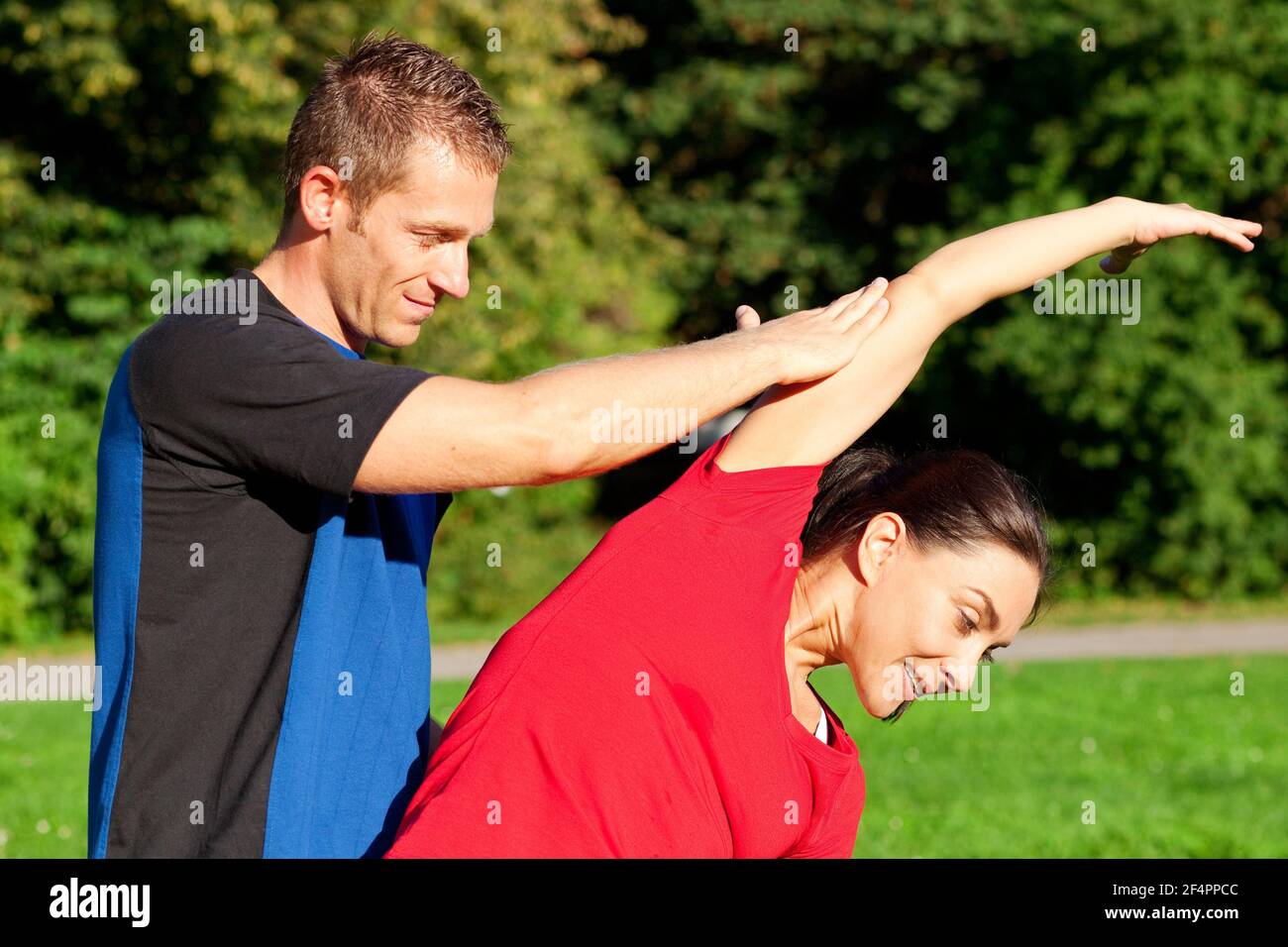 Woman does outdoor stretching with her personal trainer on a great ...