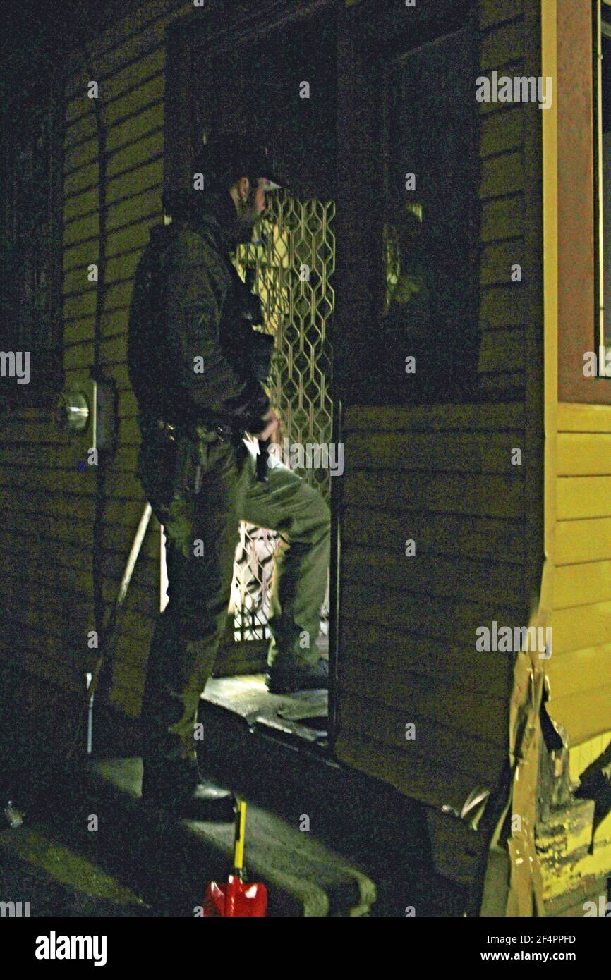 A police officer searches the back of a house at night, Detroit ...