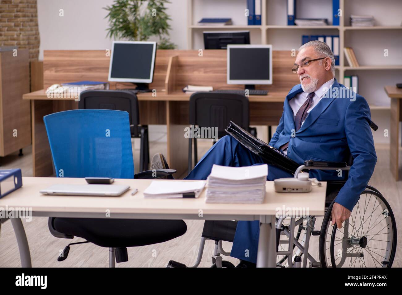 Old male employee in wheel-chair working in the office Stock Photo - Alamy
