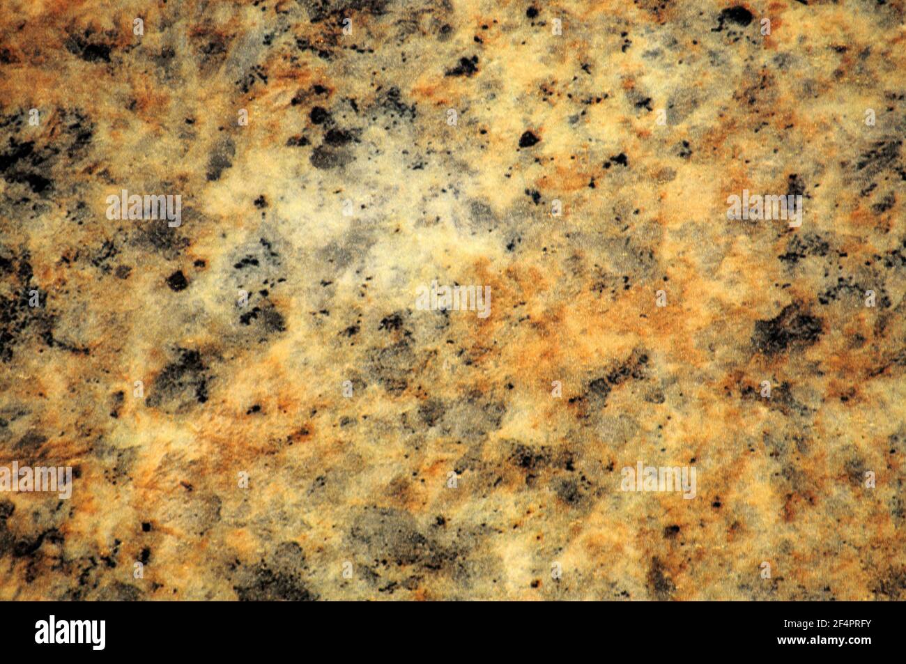 Yellow granite, polished surface of natural stone with black splashes ...