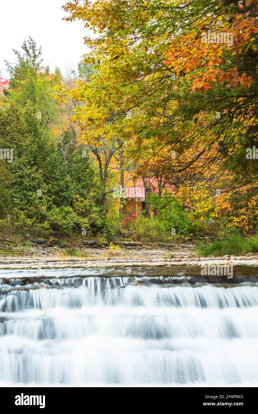 Rivière de l'Achigan with cascading waterfall and old circa 1850 yellow ...