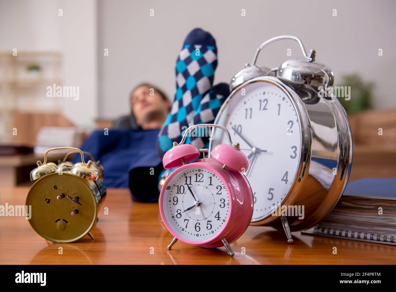 Young businessman sleeping in the office in time management concept ...
